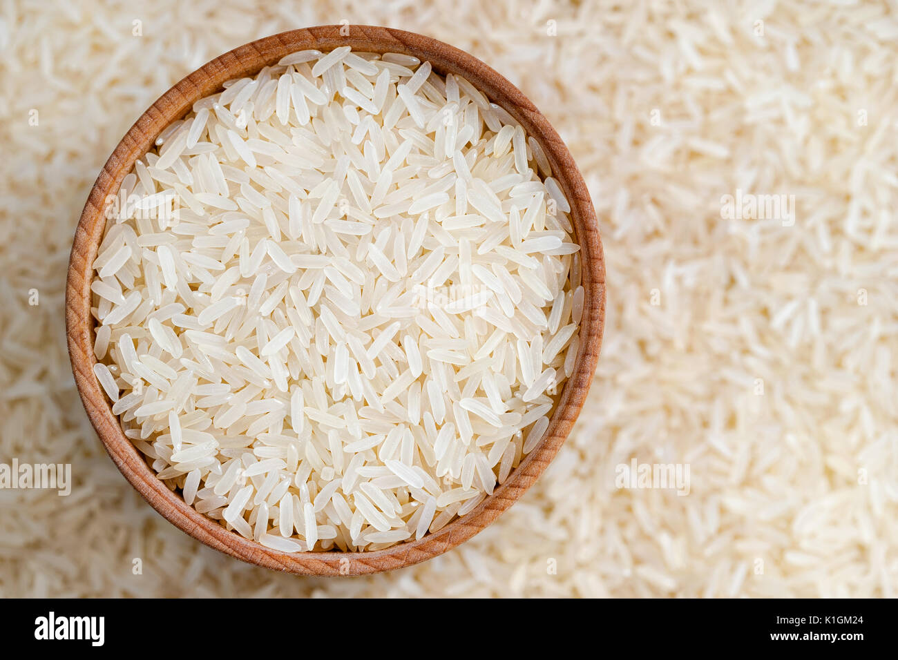 Wooden bowl filled long parboiled rice on blurred background. Close up ...