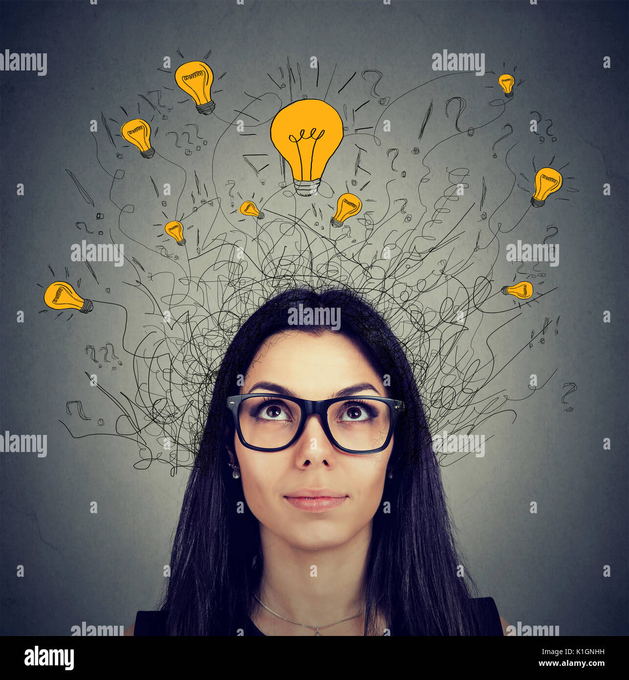 Serious woman in glasses with many ideas light bulbs above head looking ...