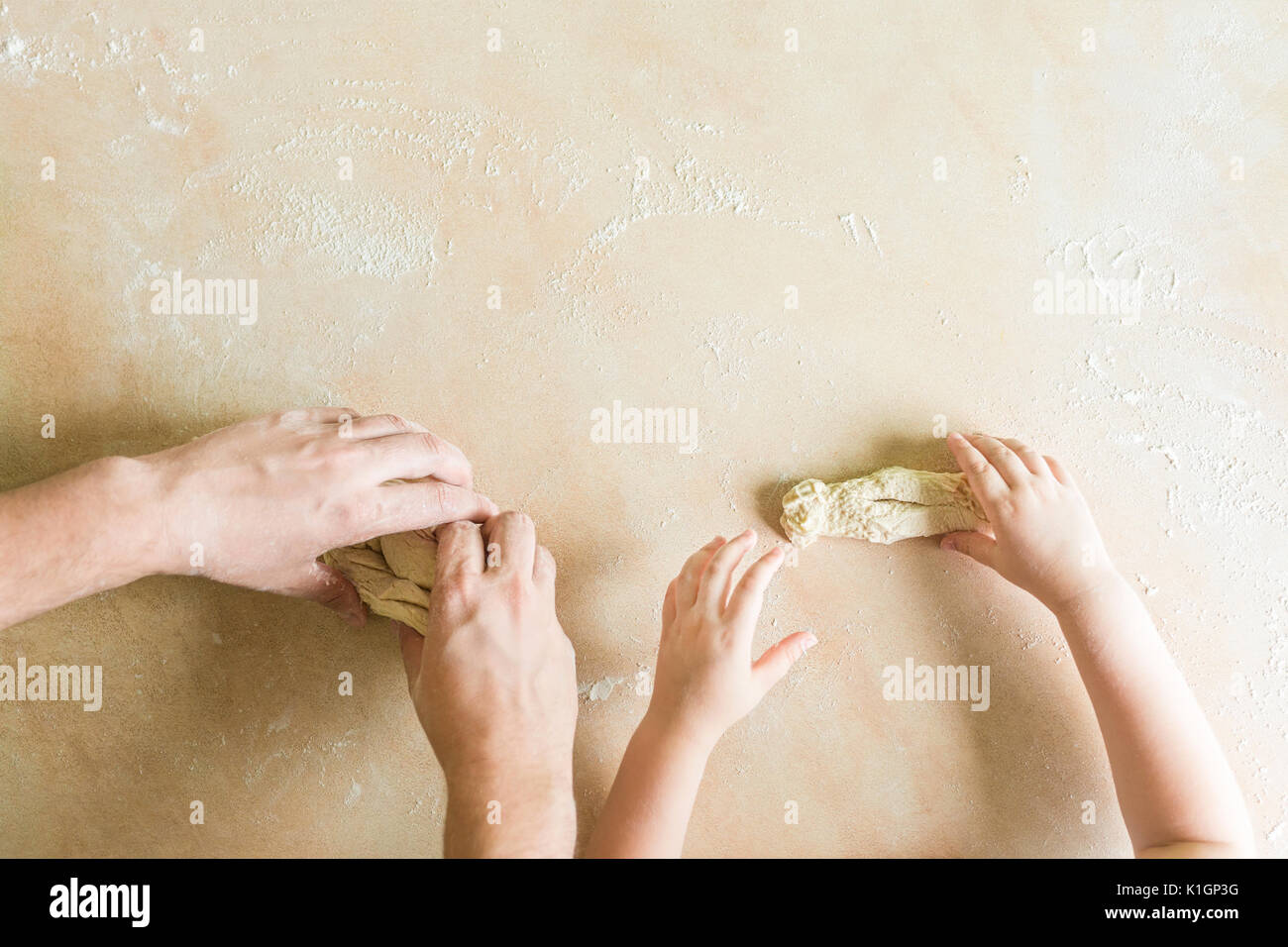 Top view shoot of children's and dad's hands makes raw dough. Learning ...