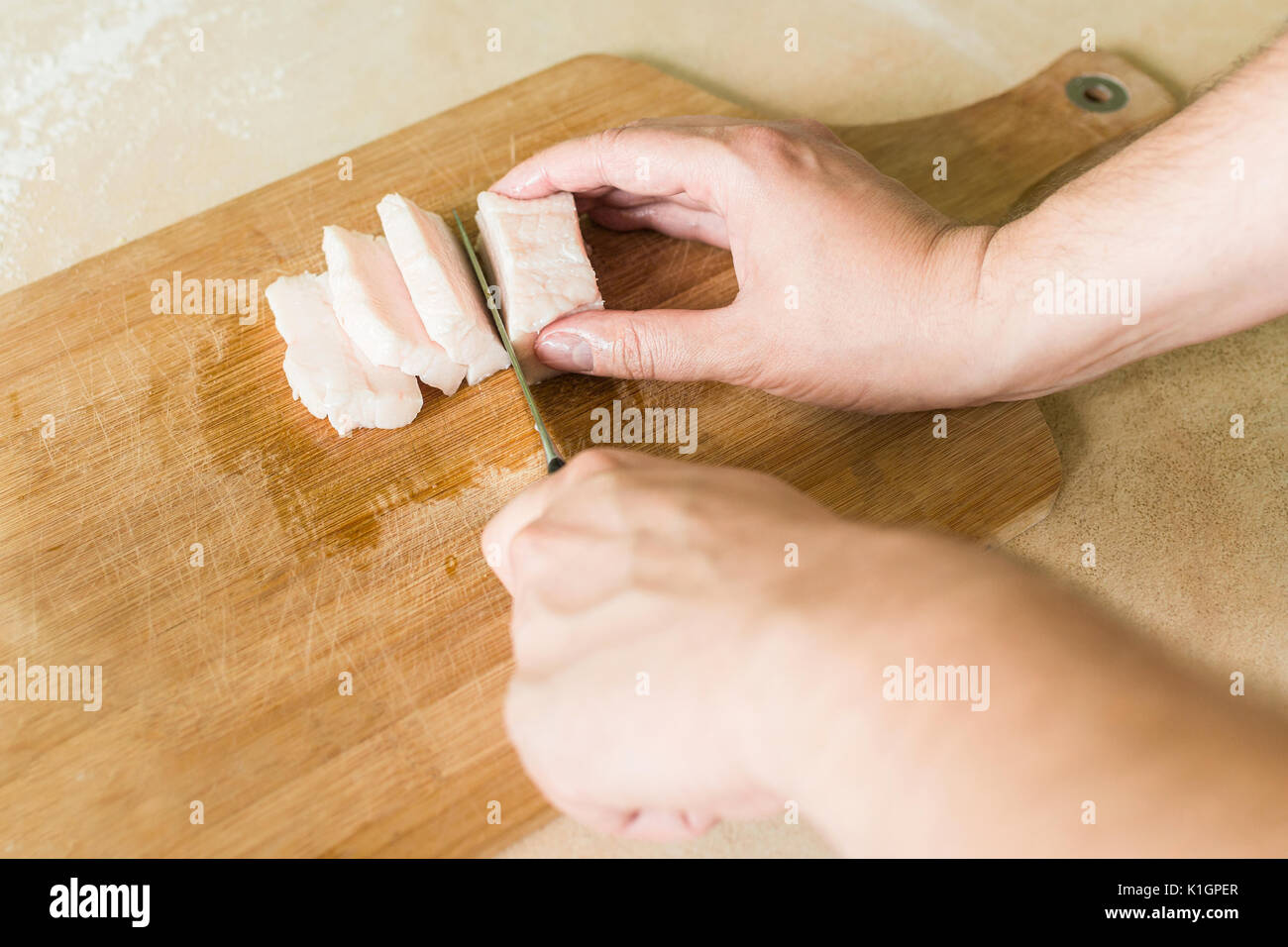 The top view of a man's hand cuts a piece of raw pork fat on slices ...