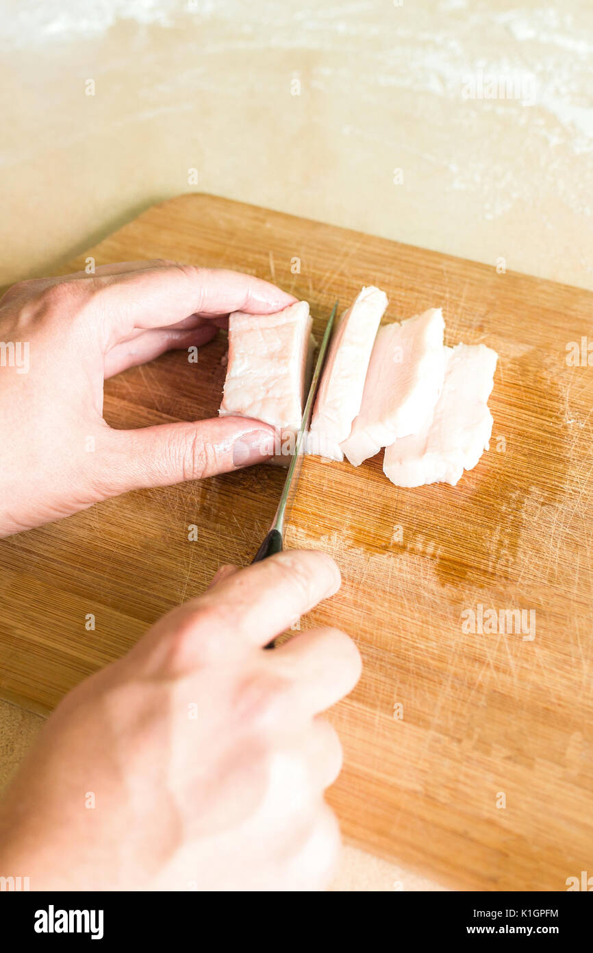 The top view of a man's hand cuts a piece of raw pork fat on slices ...