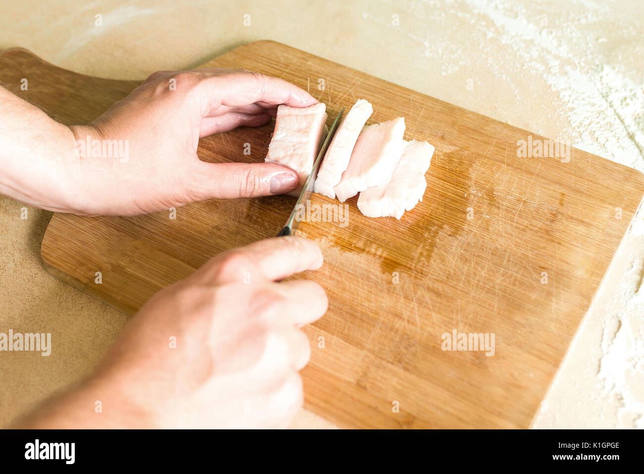 The top view of a man's hand cuts a piece of raw pork fat on slices ...