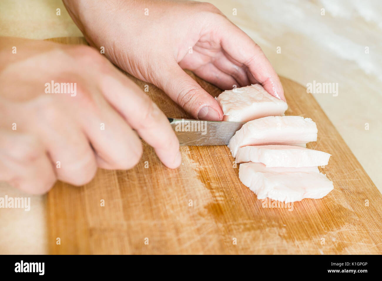 The side view of a man's hand cuts a piece of raw pork fat on slices ...