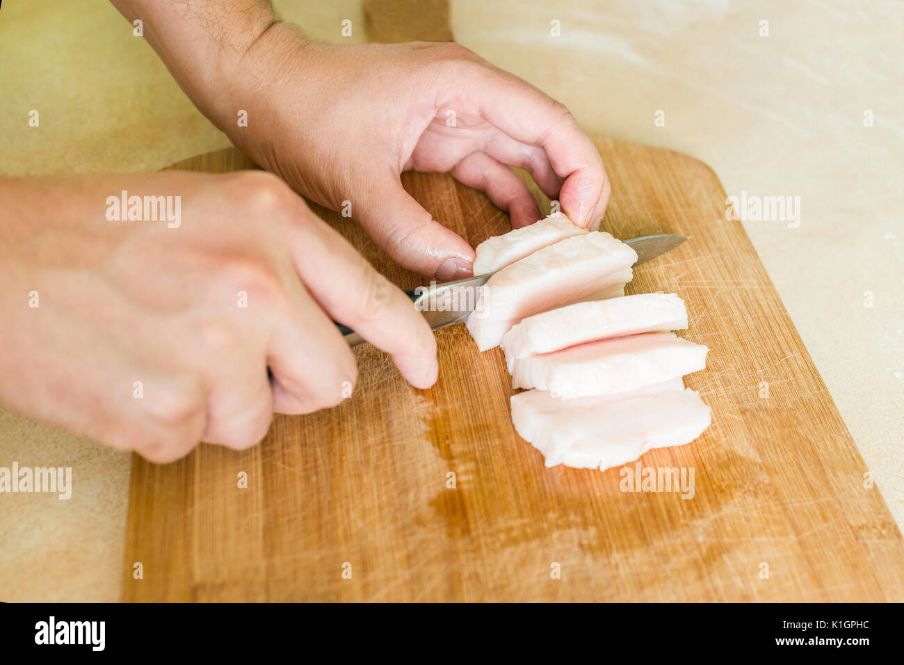 The side view of a man's hand cuts a piece of raw pork fat on slices ...