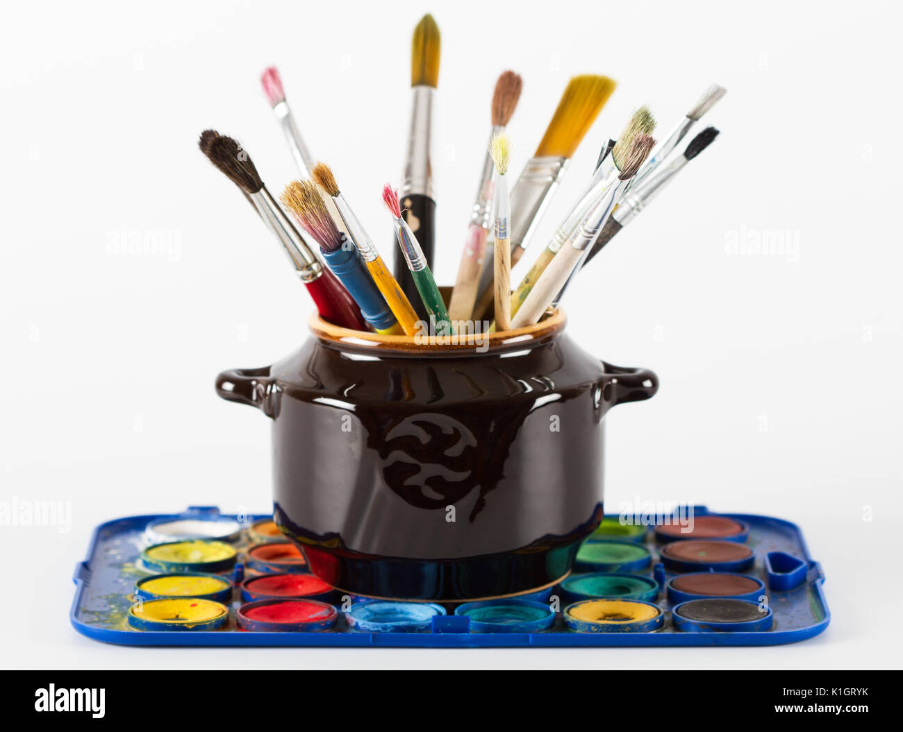 Paint brushes in clay jug and water paints on white background Stock ...