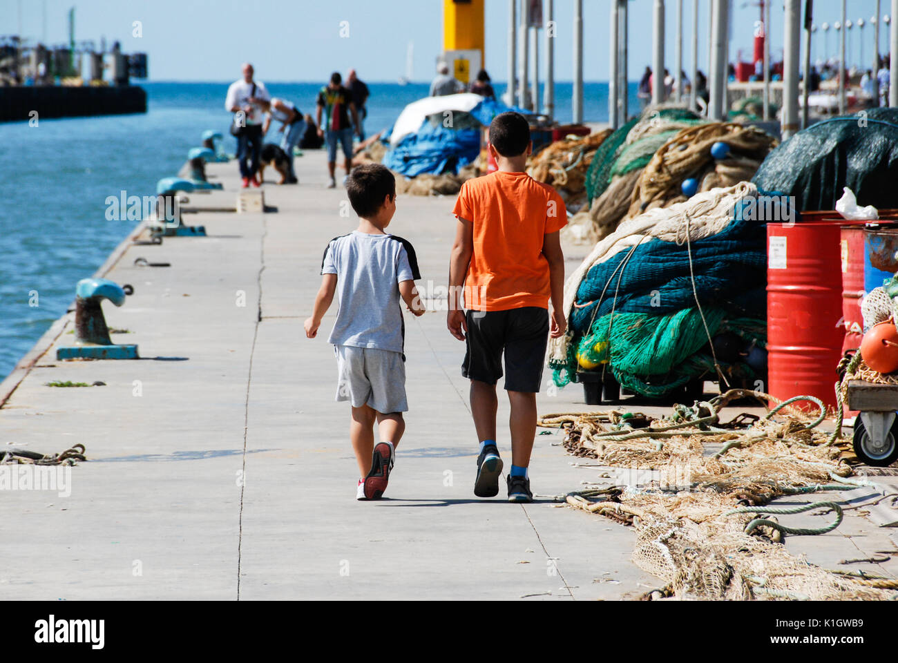 Two children stroll on the dock among the fishing nets on a sunny day ...