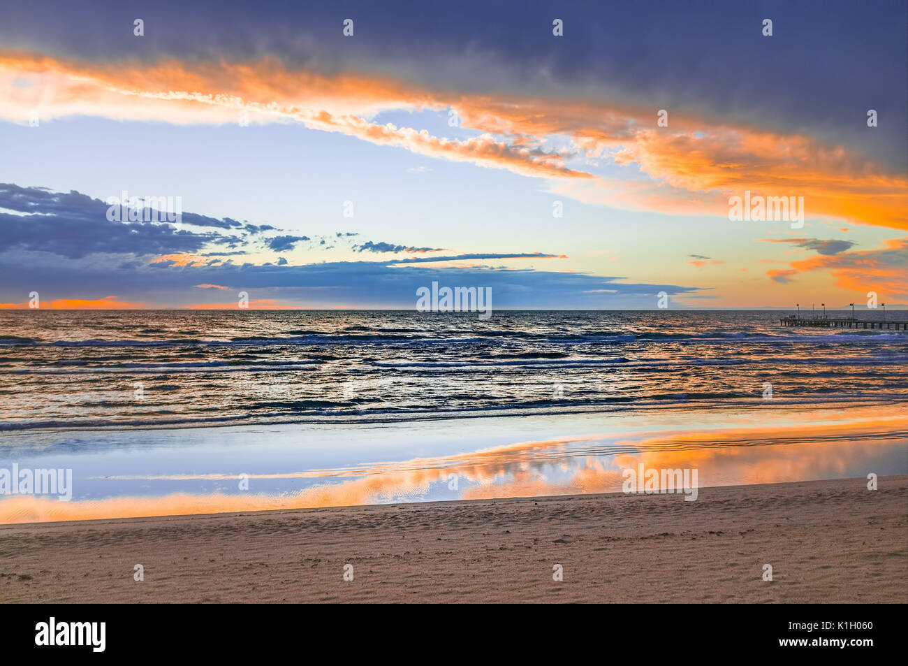 Beautiful sunset reflecting in low tide puddles at empty ocean beach ...