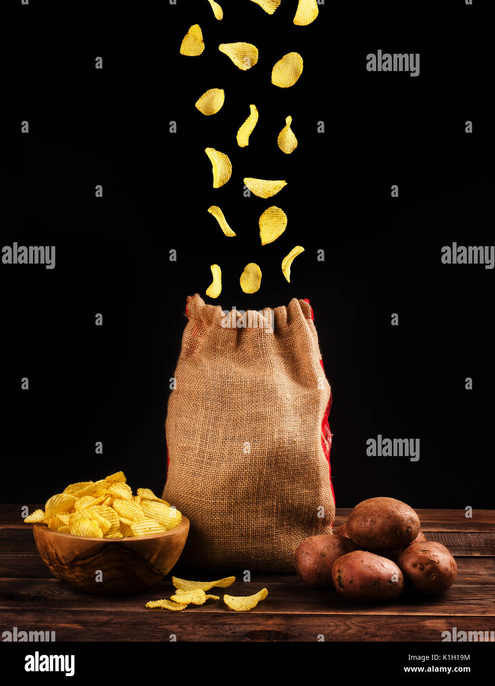 Potato chips fall into a canvas bag isolated on a black background ...