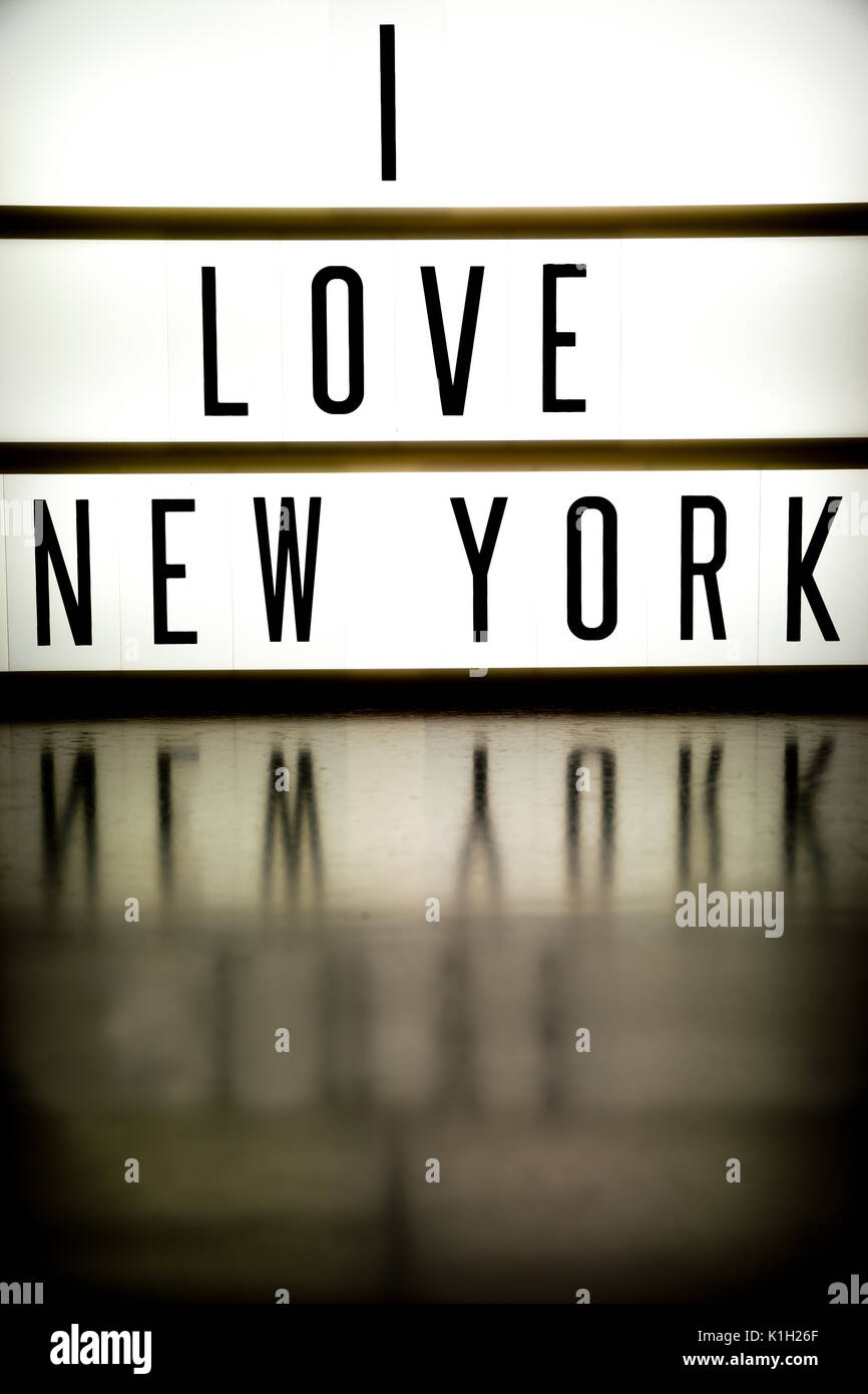 A light up board displays the phrase I LOVE NEW YORK reflected on wood ...