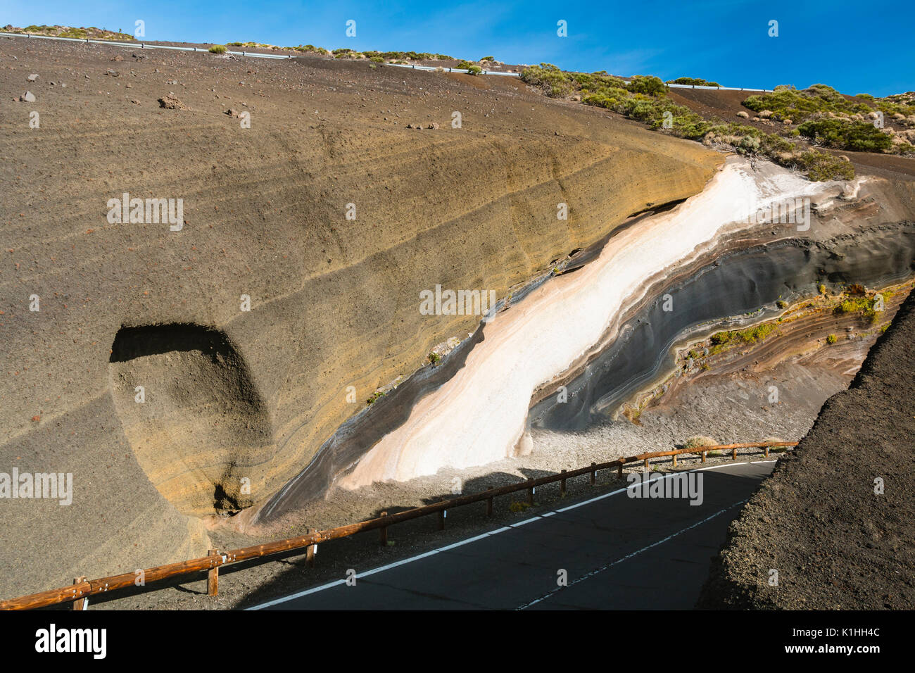 Colorful volcanic rock layers with a white stripe in a bend of the TF24 road in Tenerife, Spain ...