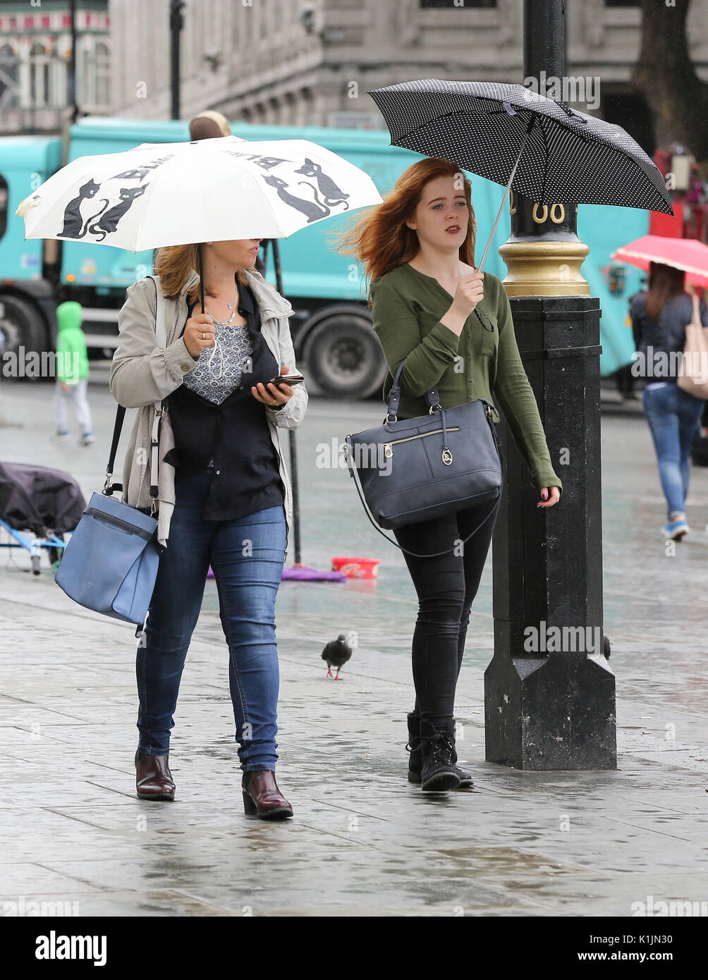 Tourists shelter from the rain in Trafalgar Square on a wet and rainy ...