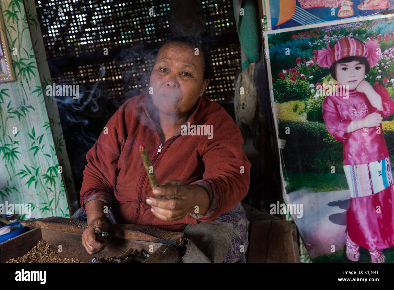A woman offers a lit cheroot - Burmese cigar, at her home workshop in ...