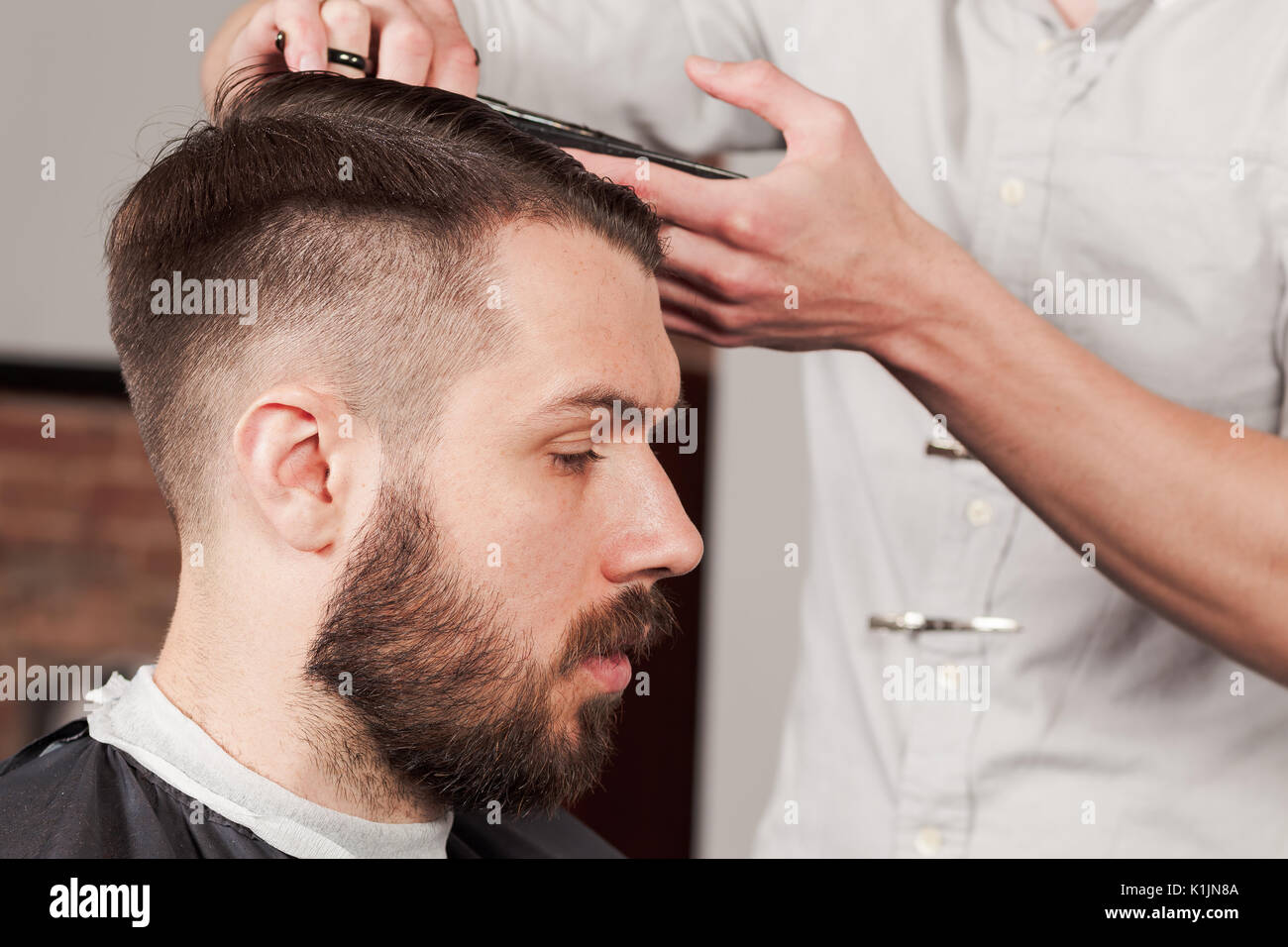The hands of barber making haircut to young man in barbershop Stock ...