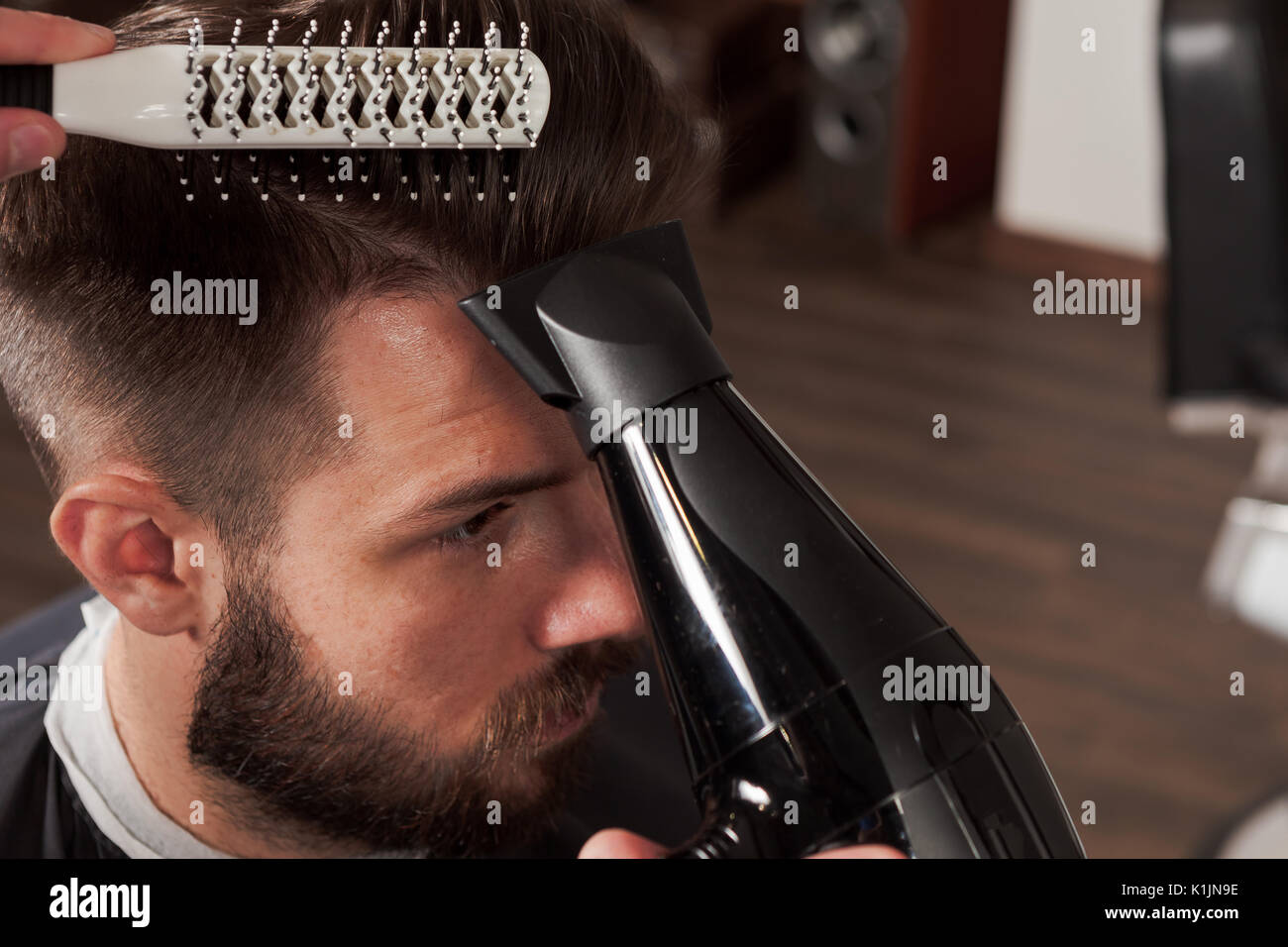The hands of barber making haircut to young man in barbershop Stock ...
