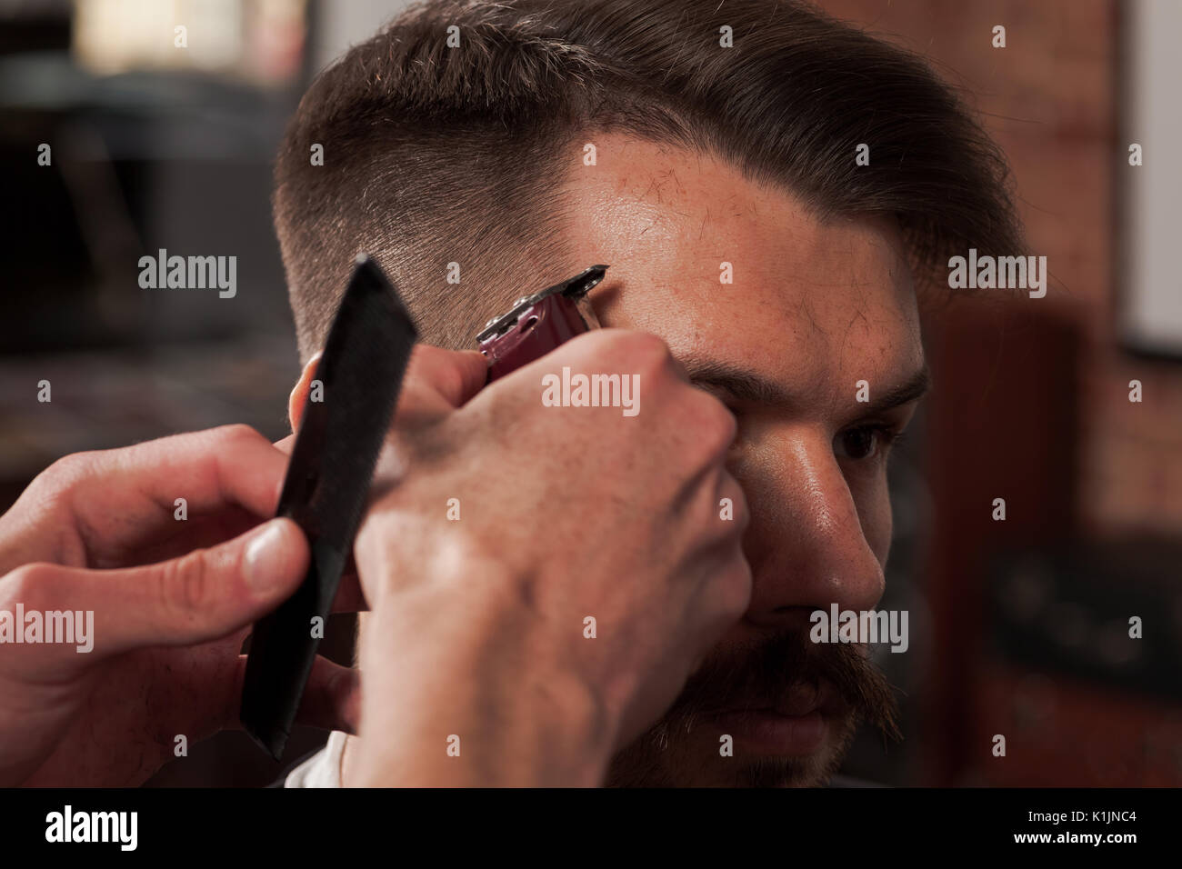 The hands of barber making haircut to young man in barbershop Stock ...