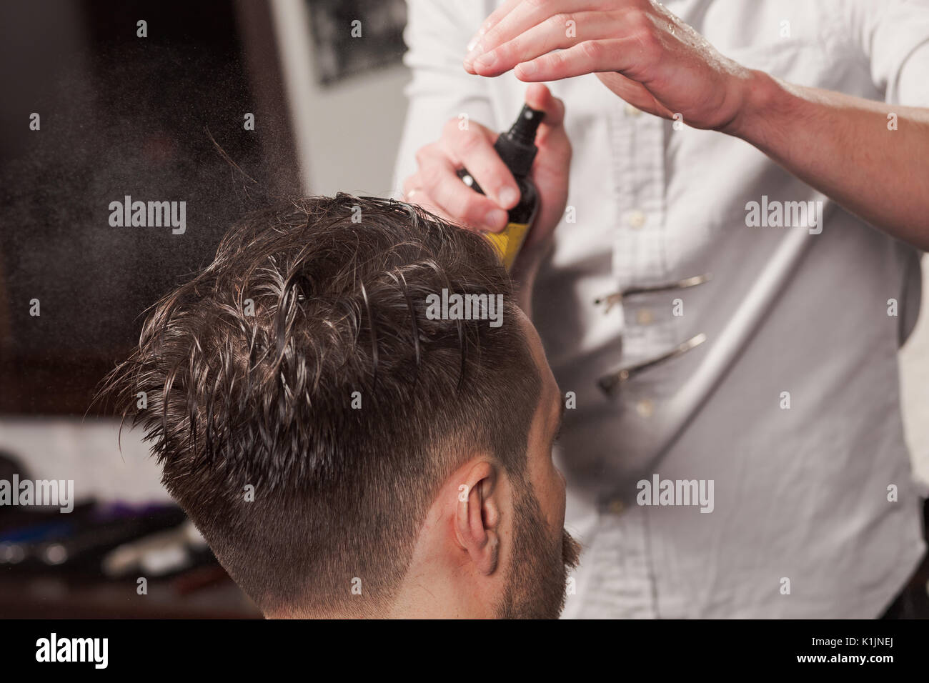 The hands of barber making haircut to young man in barbershop Stock ...