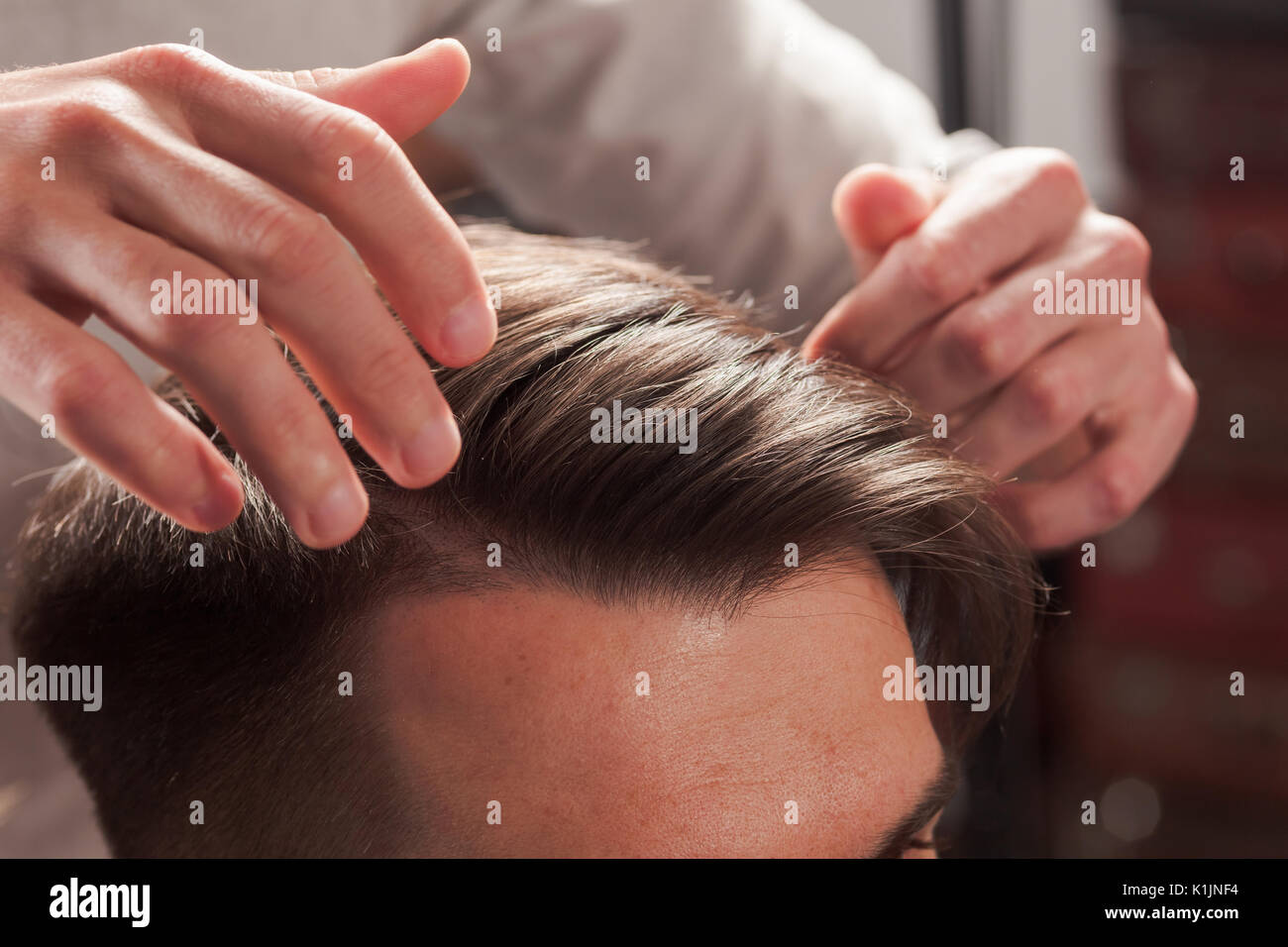 The hands of barber making haircut to young man in barbershop Stock ...