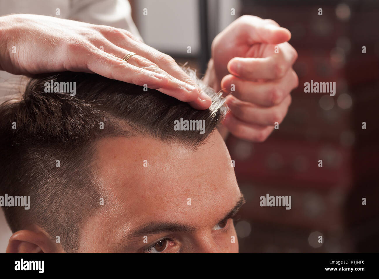 The hands of barber making haircut to young man in barbershop Stock ...