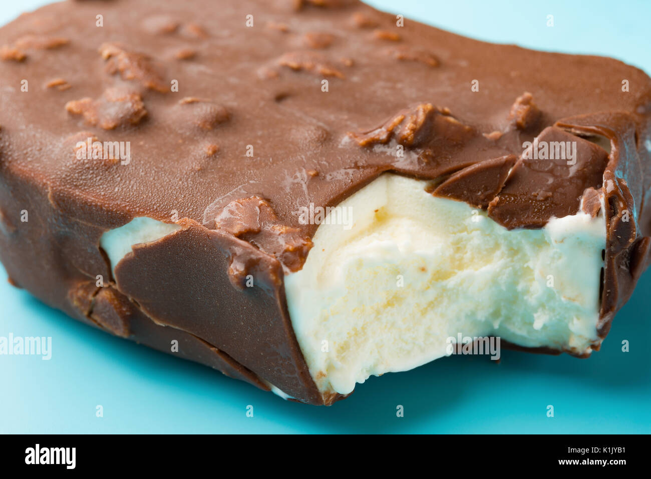 chocolate outer ice cream starts melting with a bite close up on a blue ...