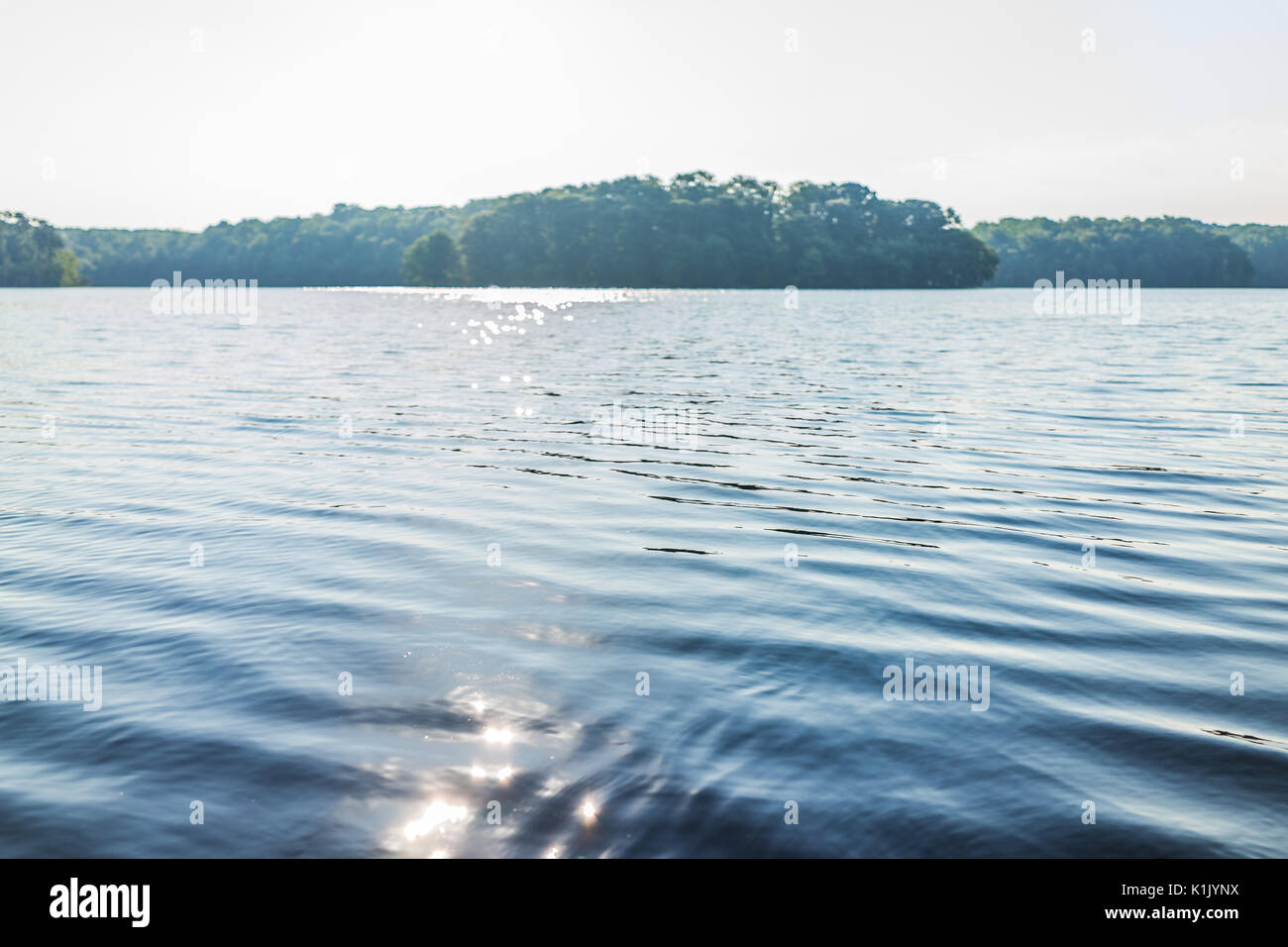Sun path reflection over lake in summer on bright day with waves and ...