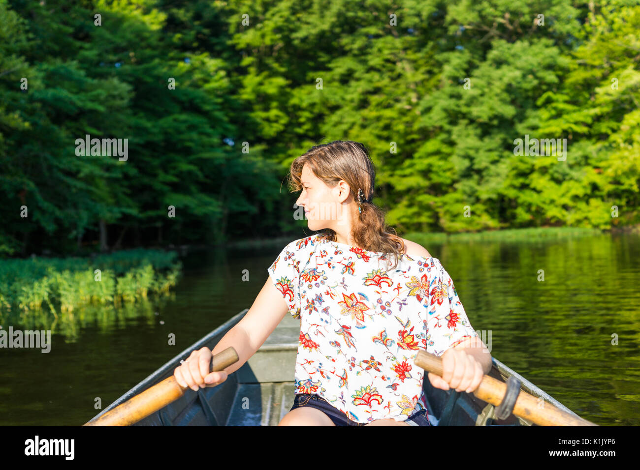 Happy smiling young woman rowing boat on lake in Virginia during summer ...