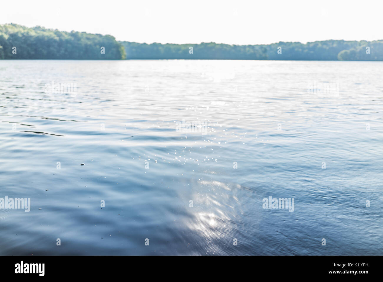 Sun path reflection over lake in summer on bright day with waves and ...