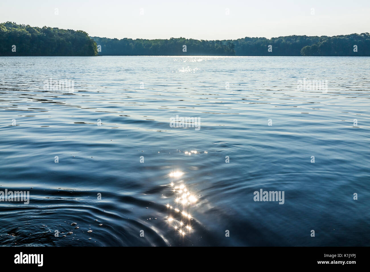 Sun path reflection over lake in summer on bright day with waves and ...