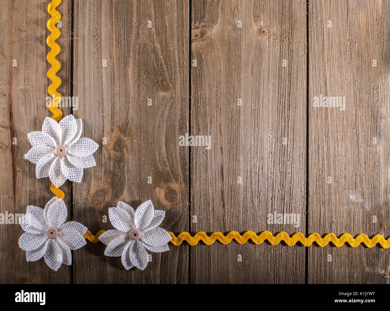 Burlap flowers and yellow rickrack for a corner border on wood Stock ...