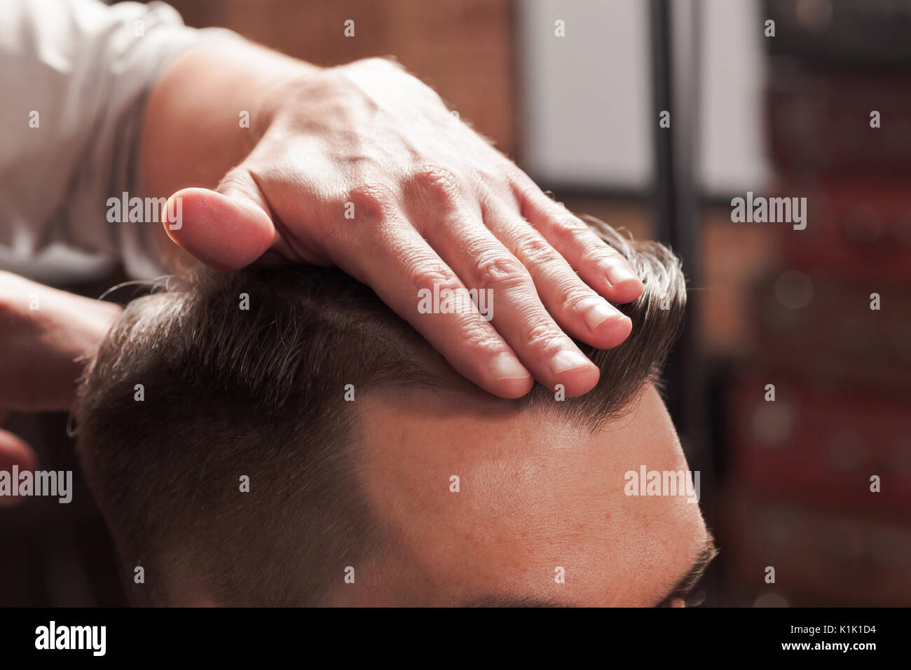 The hands of barber making haircut to young man in barbershop Stock ...