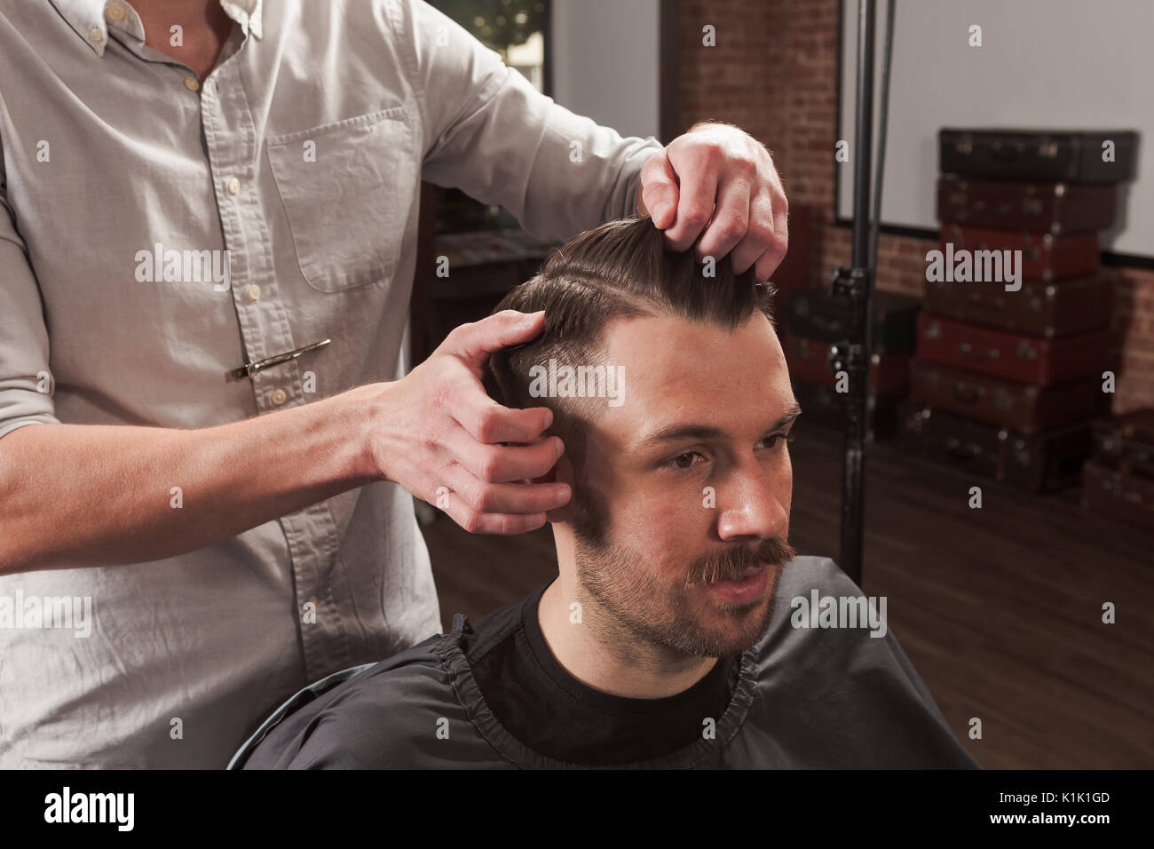 The hands of barber making haircut to young man in barbershop Stock ...