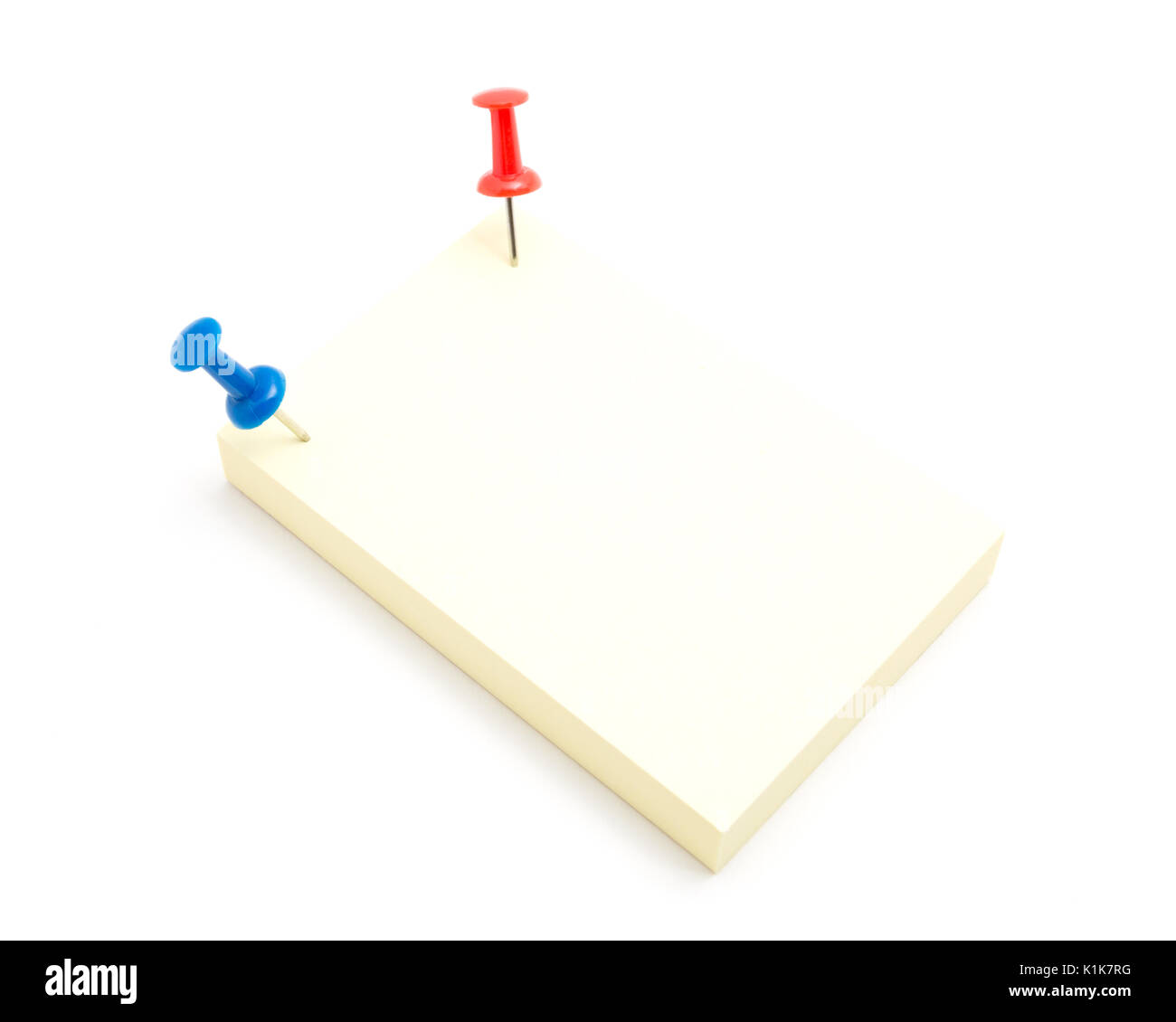Two color push pins and yellow sticky note on isolated white background ...