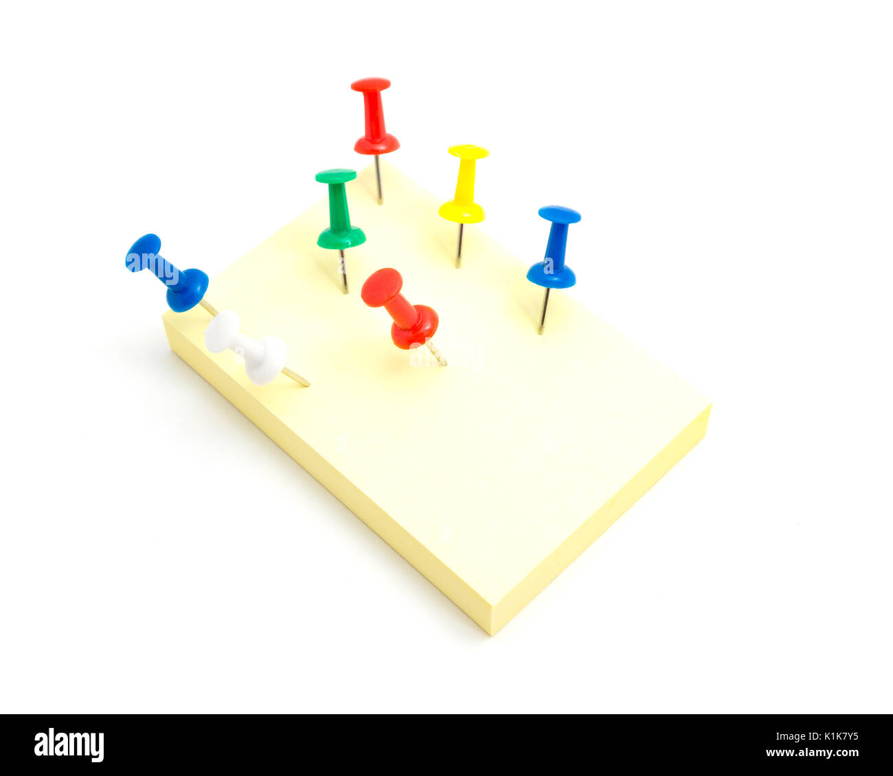 Seven push pins and yellow sticky note on isolated white background ...