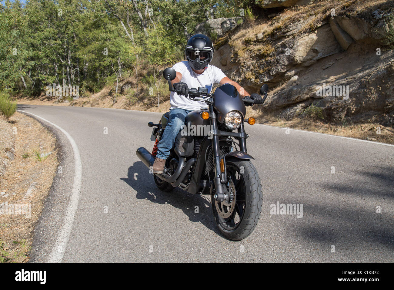 Side view of man sitting on parked custom motorcycle on road in ...