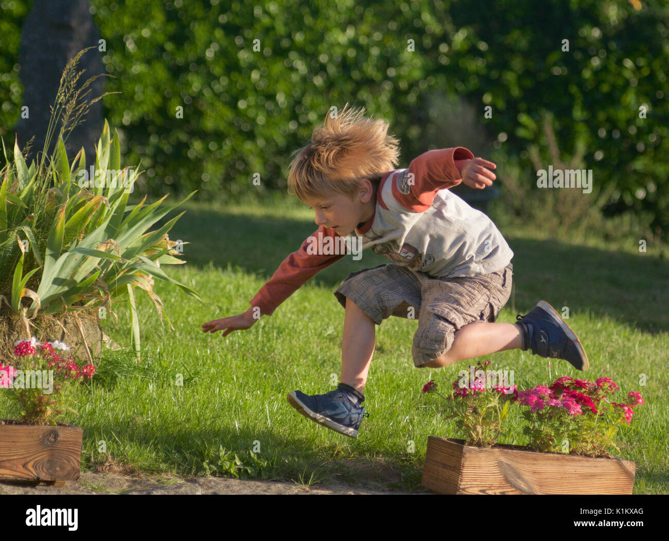 Young boy leaping over flowers Stock Photo - Alamy