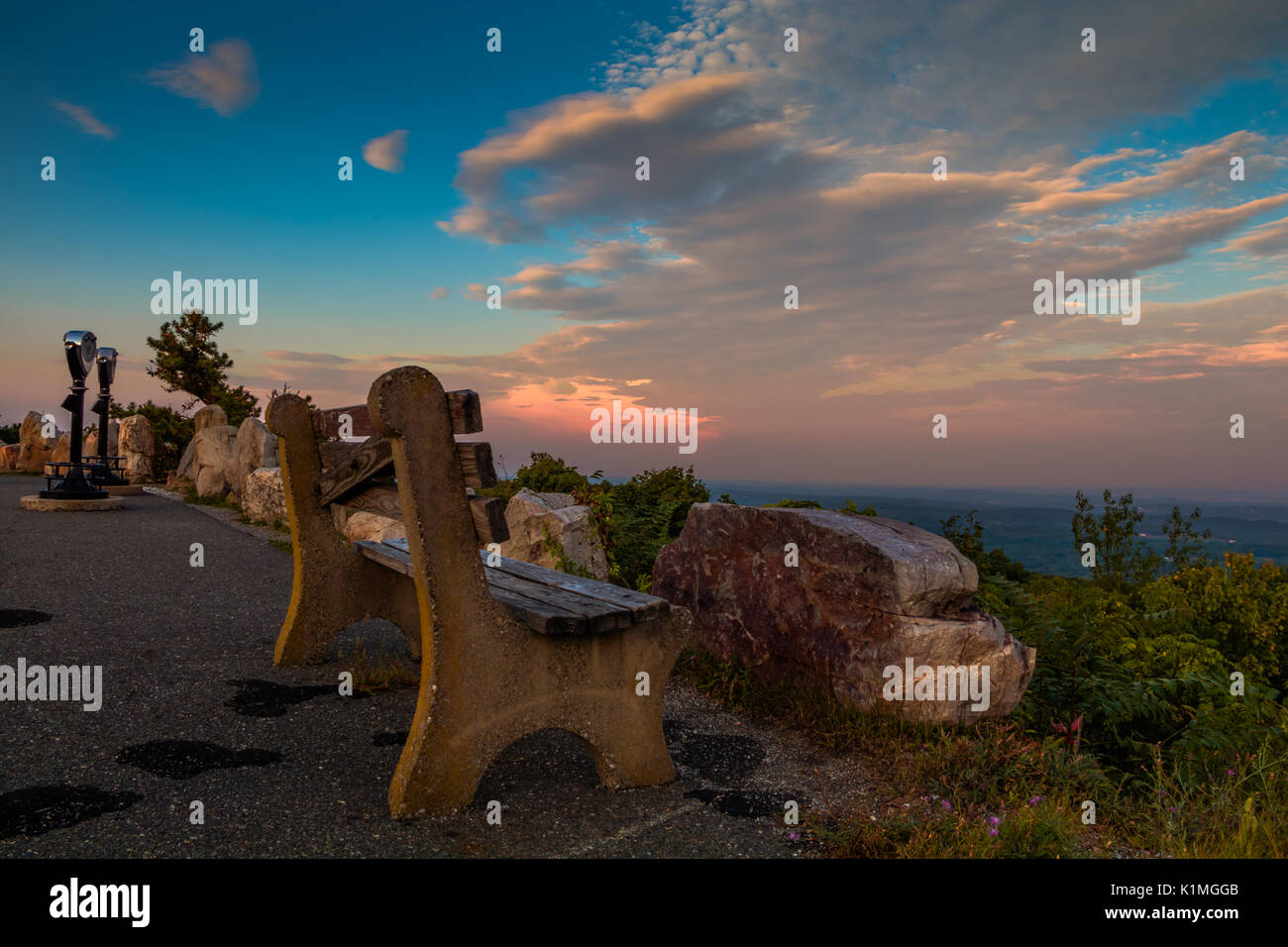 Lone bench faces majestic sunset in early fall as the sun sets at the ...