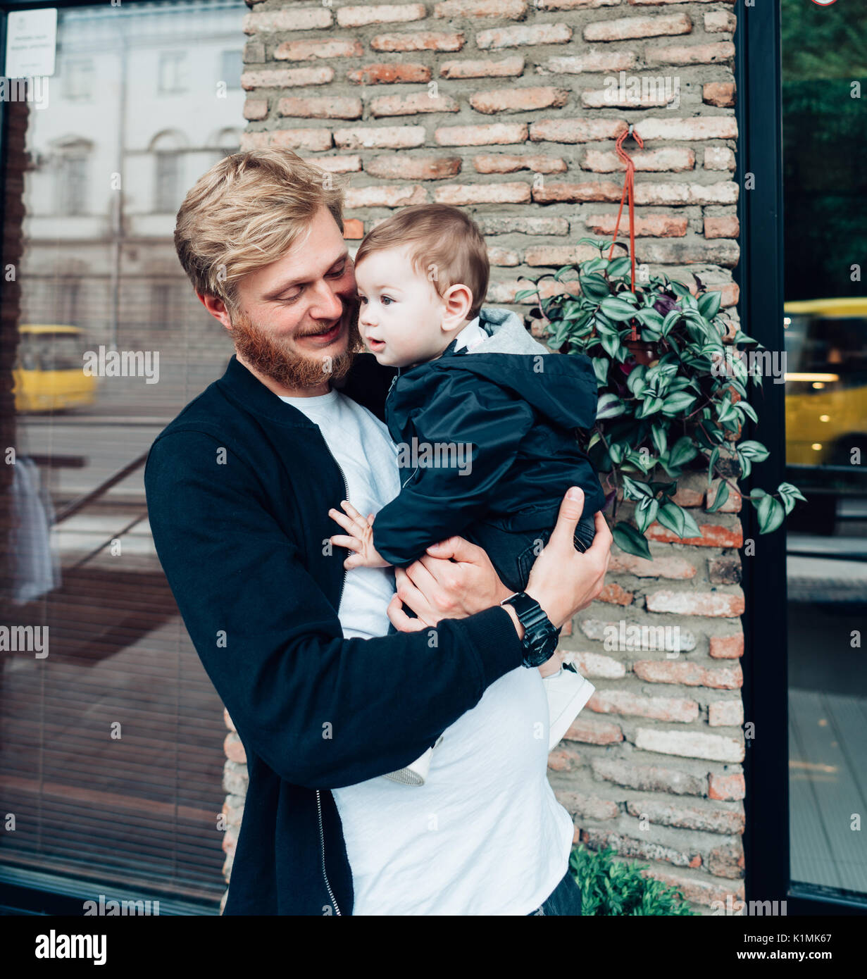 Dad with a small son in his arms against the wall on the street Stock ...