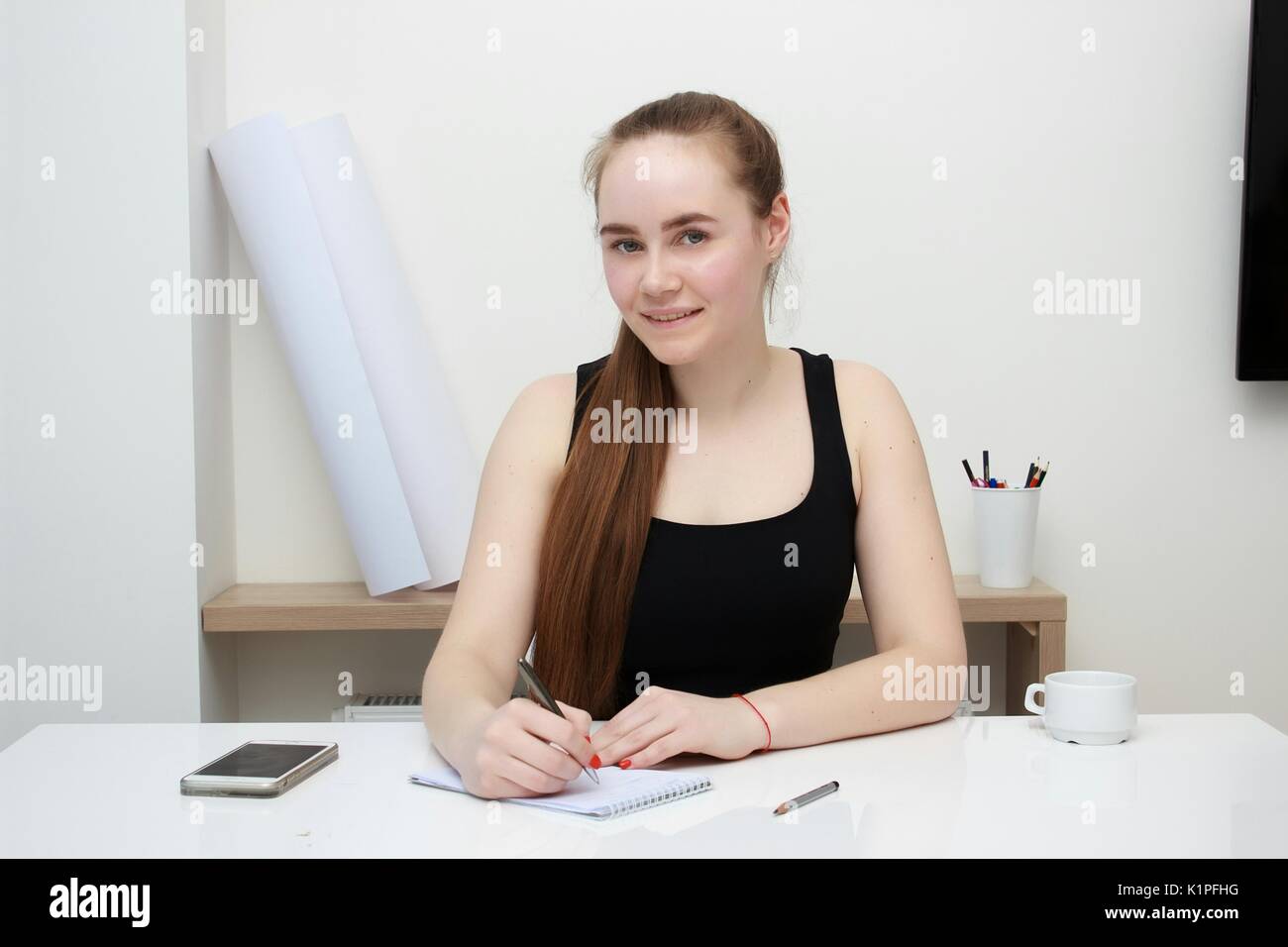 Portrait of a beautiful young smiling student doing some paperwork ...