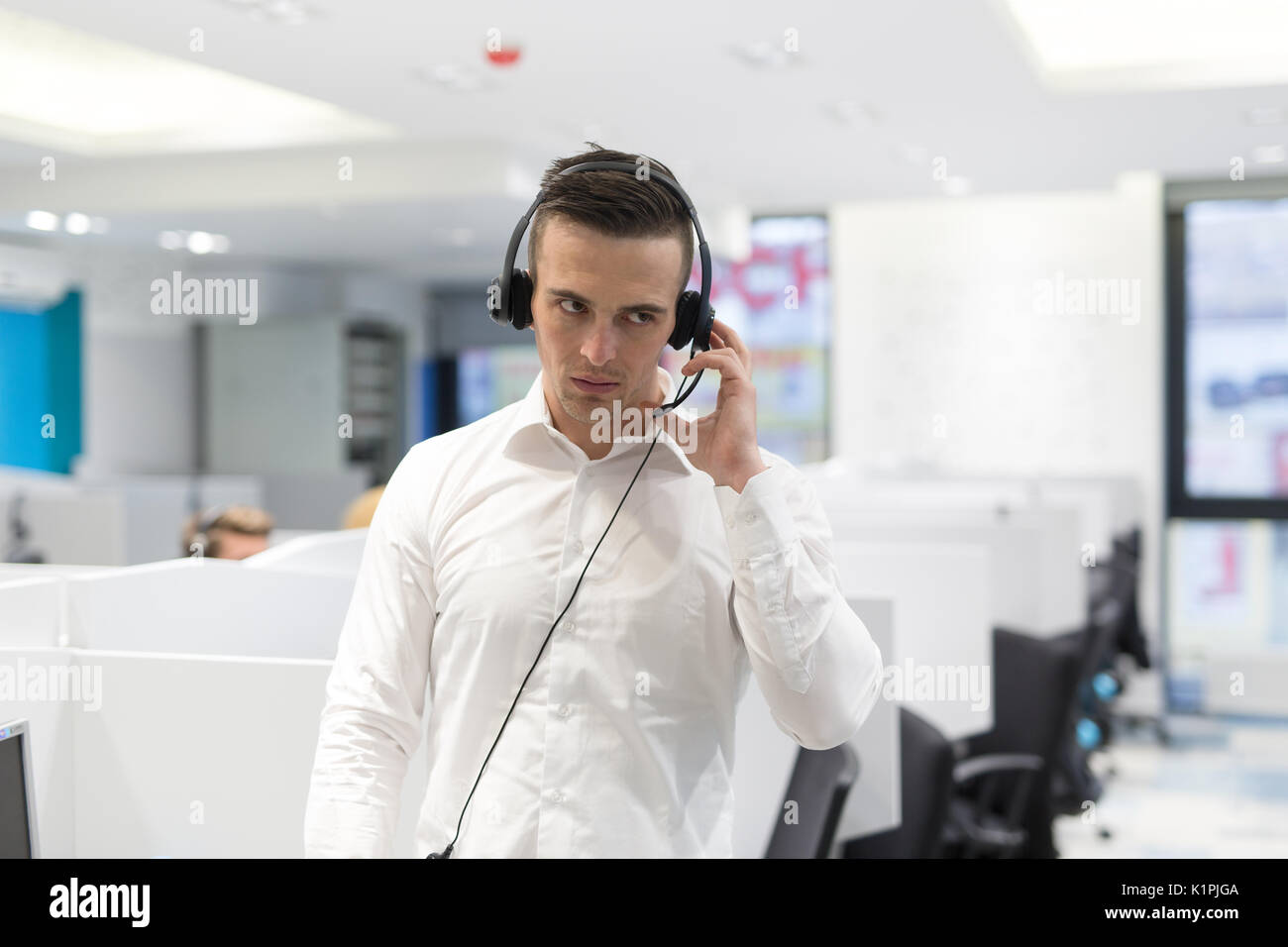 young smiling male call centre operator doing his job with a headset ...