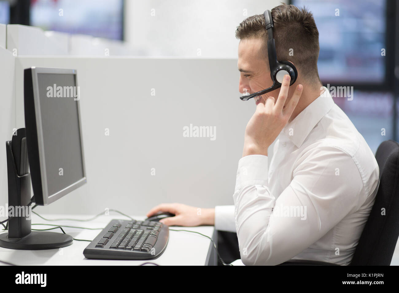 young smiling male call centre operator doing his job with a headset ...