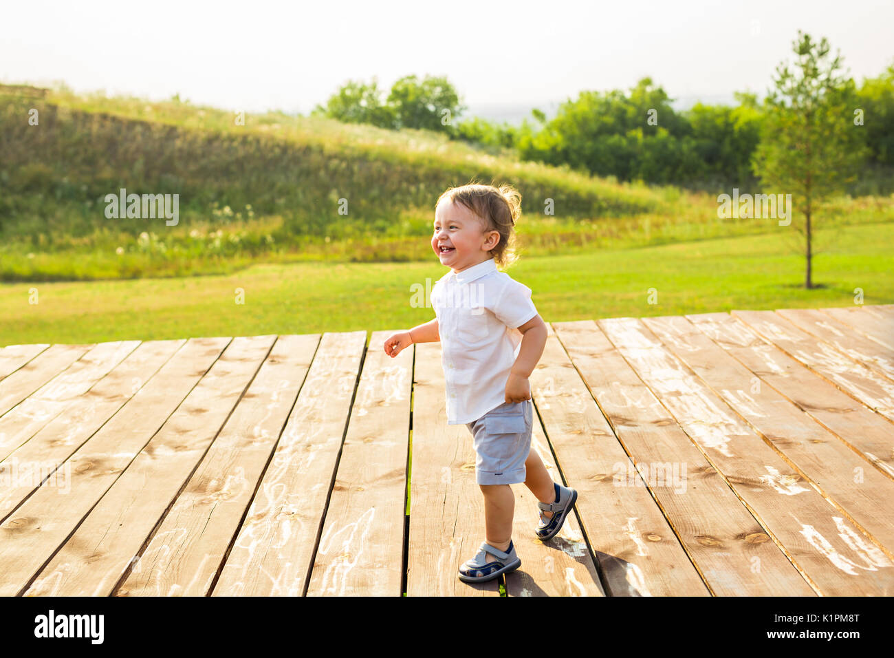 smiling boy in the field at sunny summer morning. boy in white shirt ...