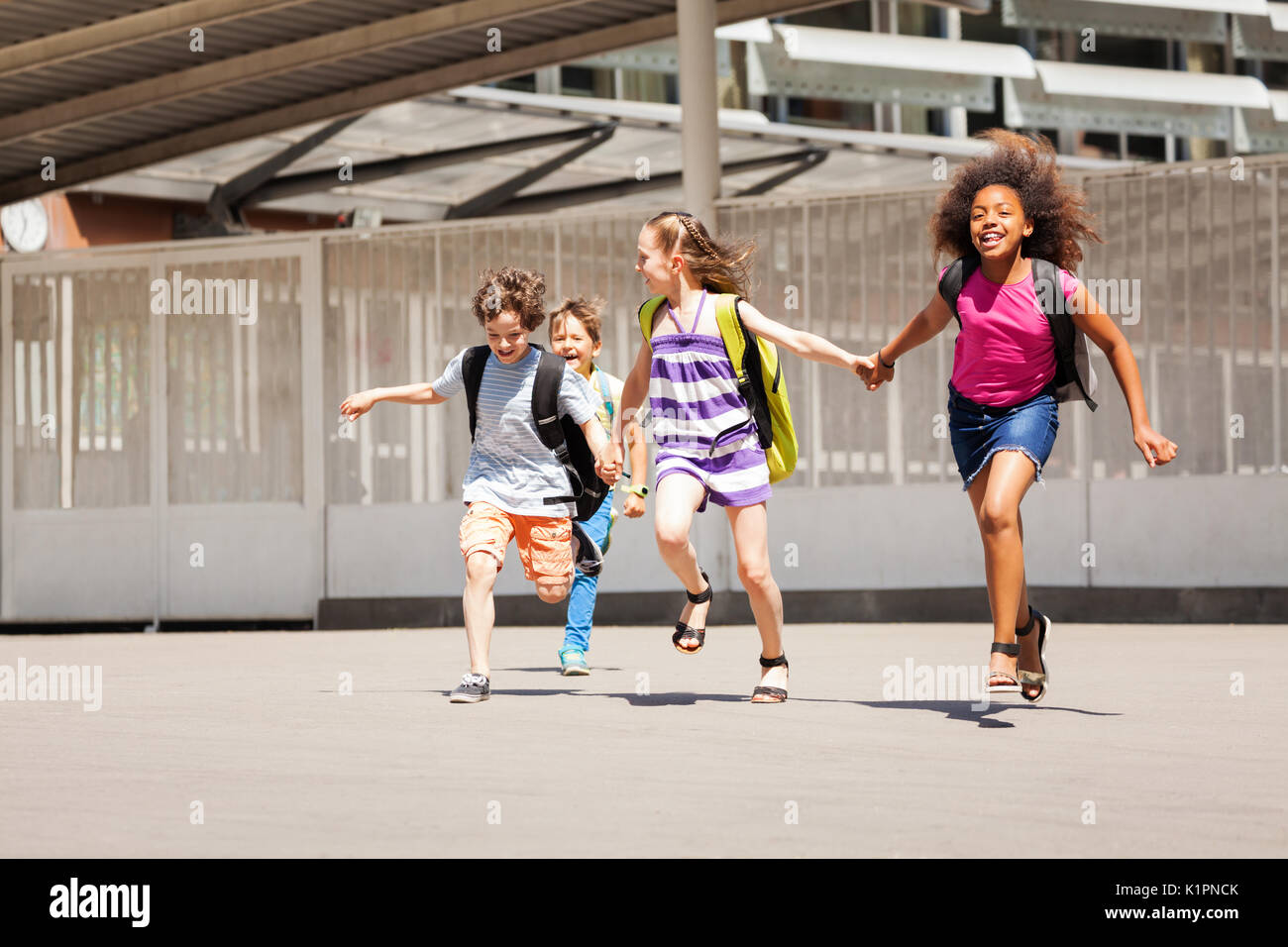 Diverse group of kids running from school happy smiling and holding ...