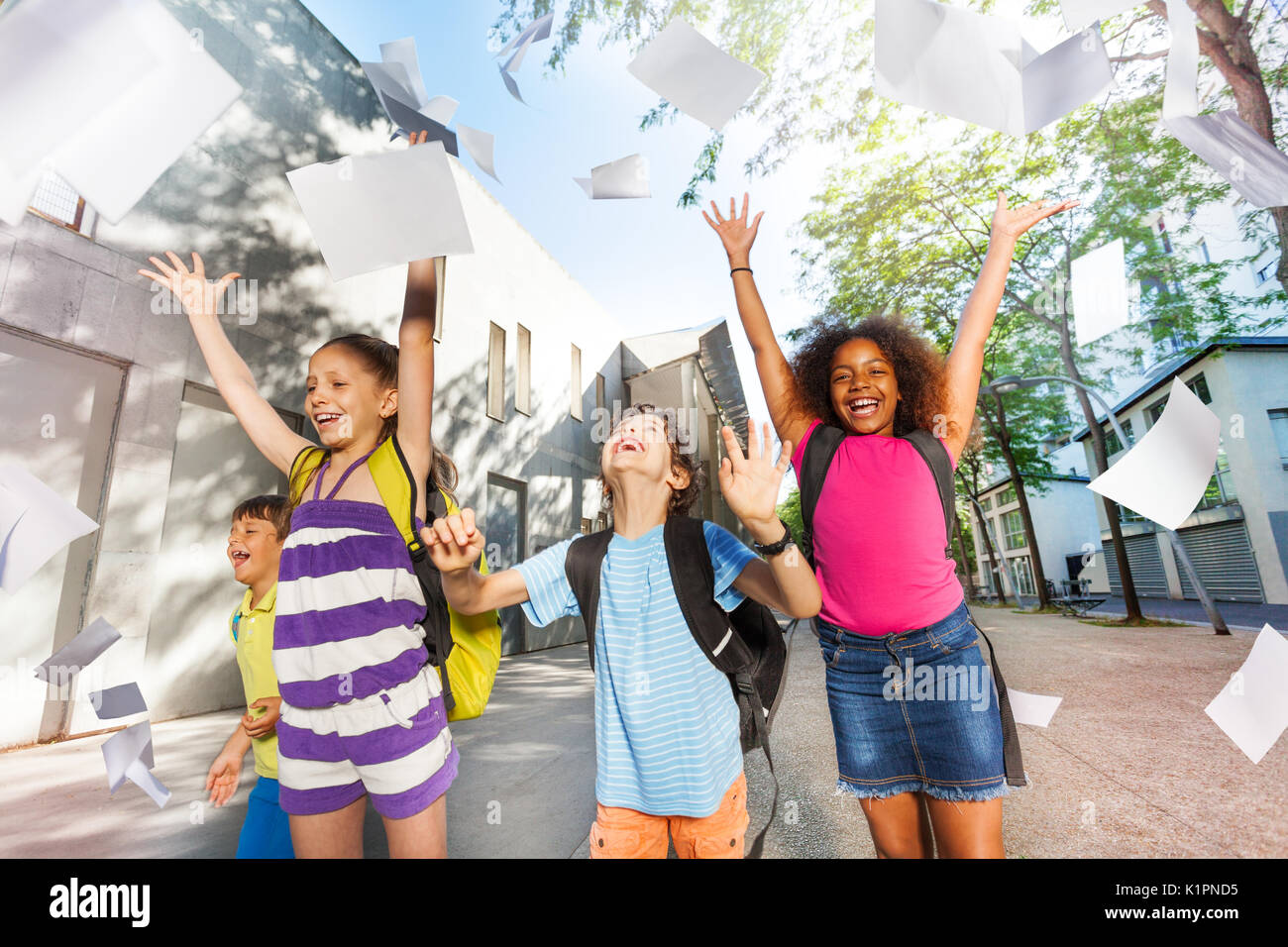 Diverse group of school kids throwing piles of paper happy exiting ...