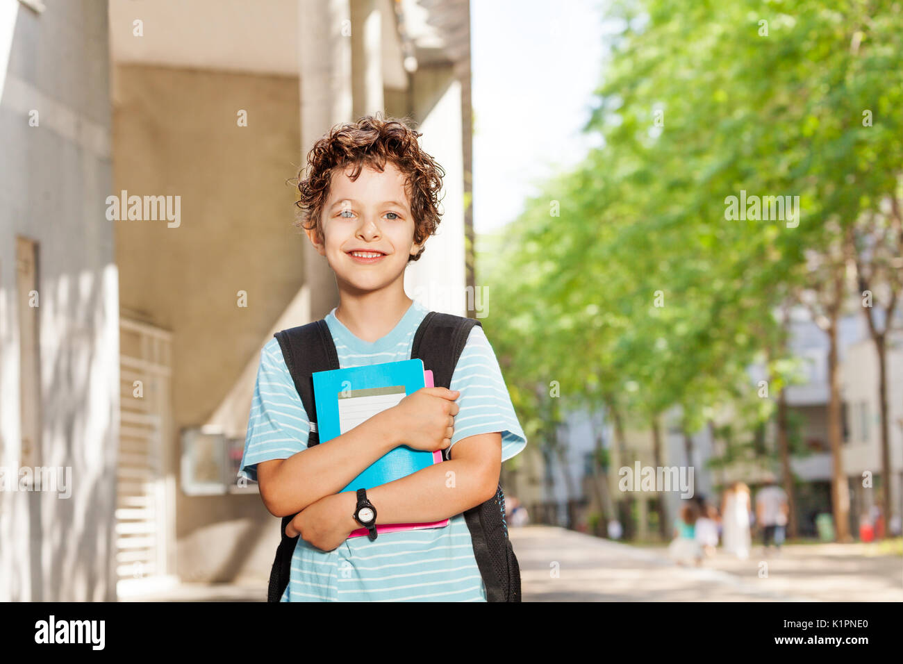 Close portrait of school boy with textbook smiling and looking at ...