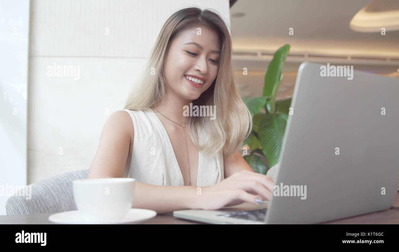 Asian businesswoman using laptop computer, smiling Stock Photo - Alamy