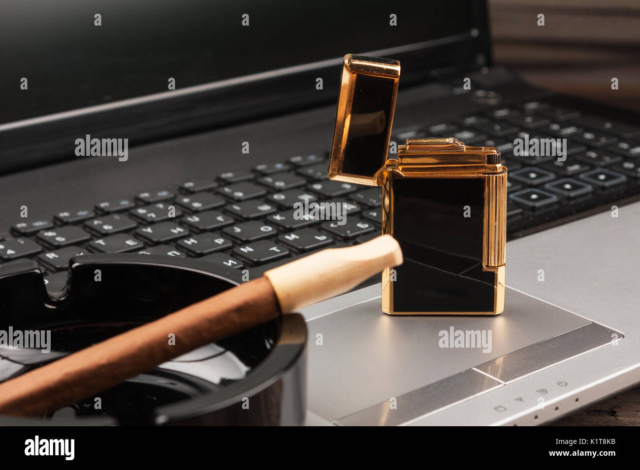 Luxurious gold lighter and cigar on laptop background. As a background ...