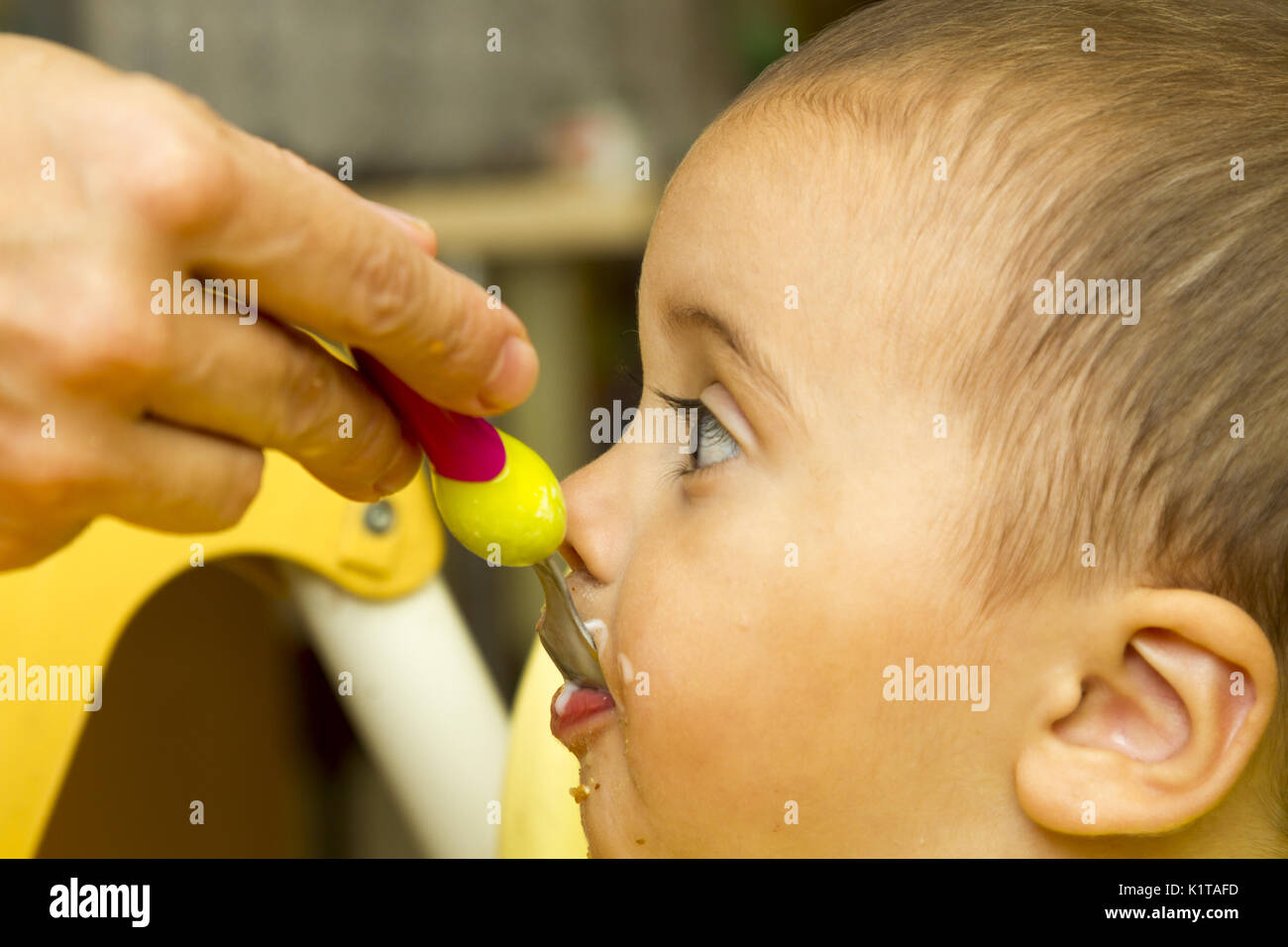 Beautiful baby eating mashed indoor face eating Stock Photo - Alamy