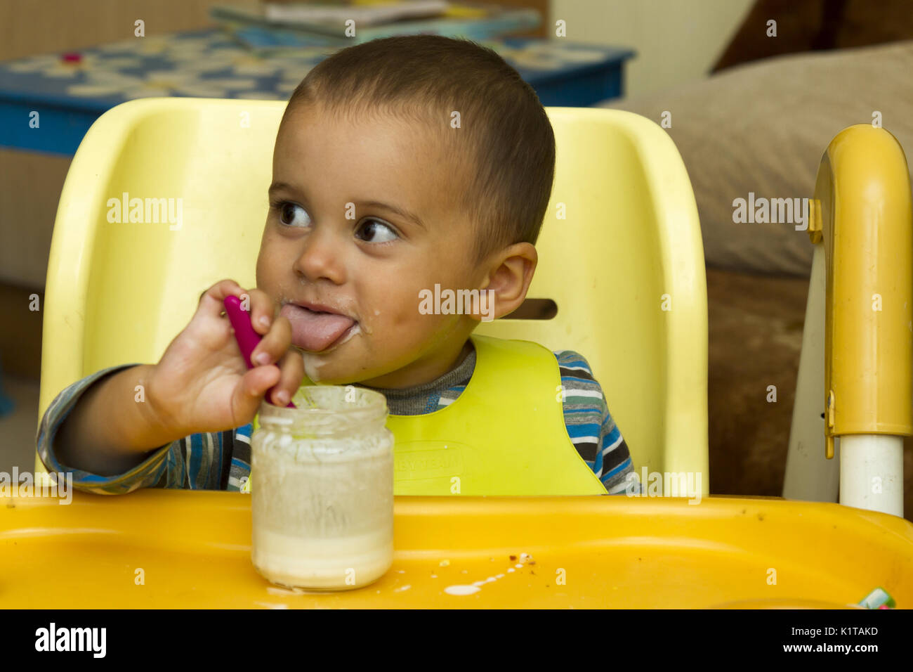 Happy baby eating food indoor face eating Stock Photo - Alamy