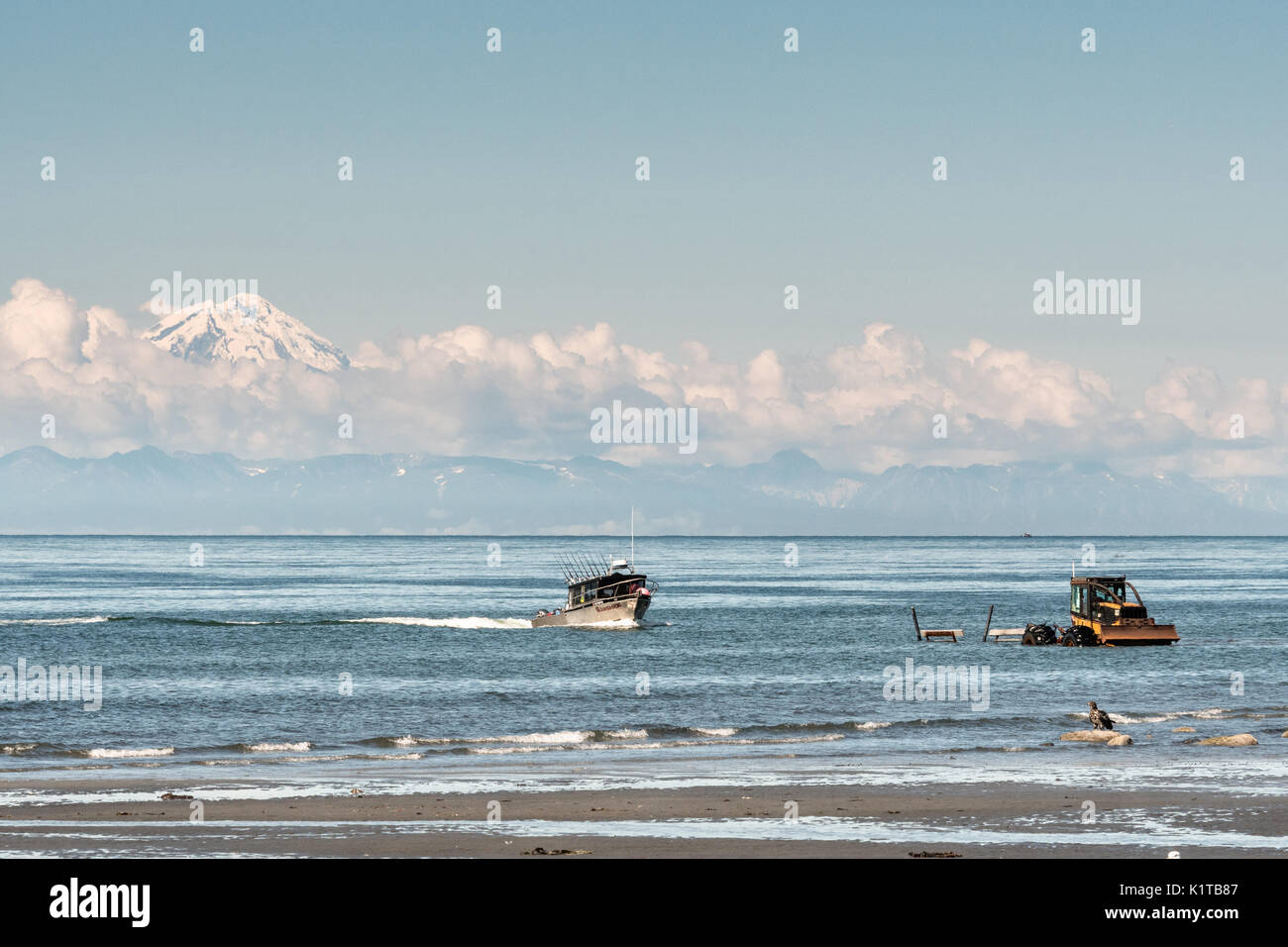 Fishing boats drive up to an awaiting tractor tug that will carry them ...