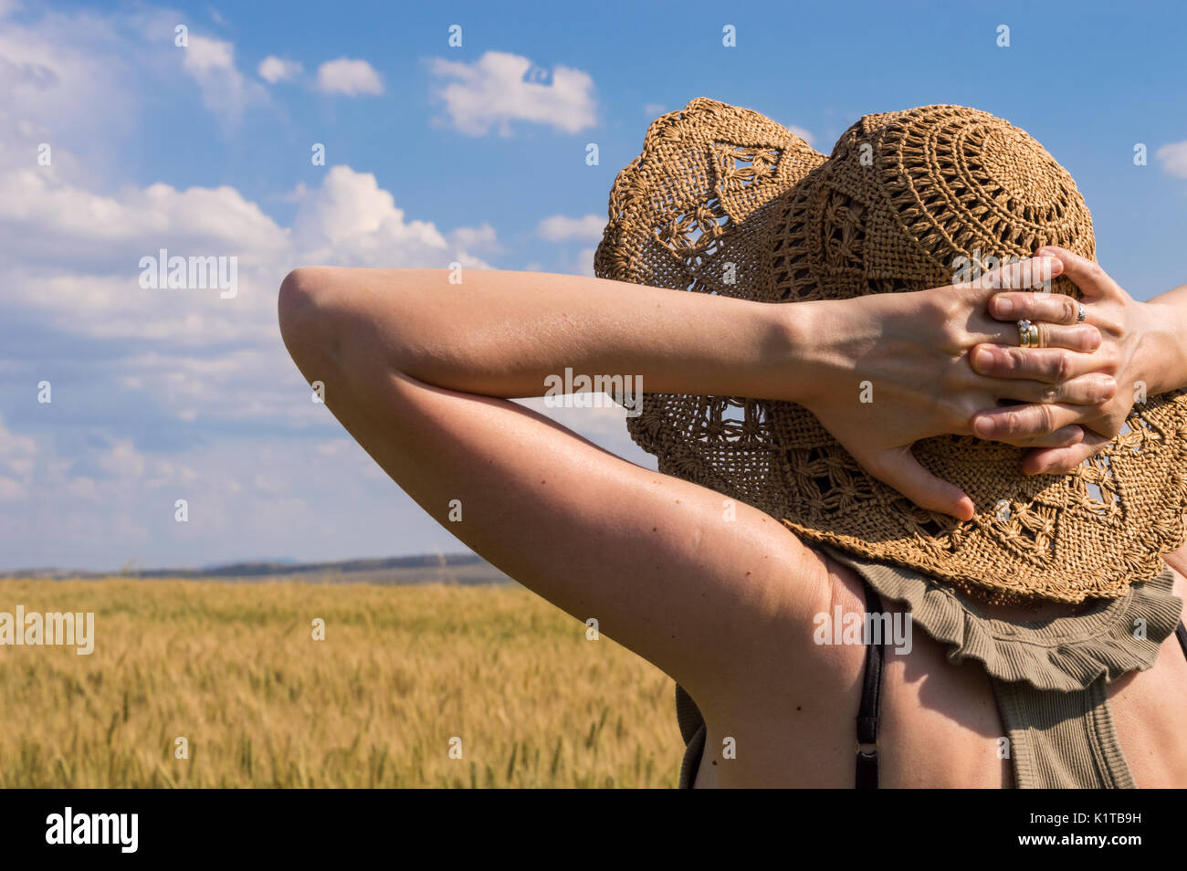 Caucasian woman with hands behind head, staring at horizon on a summer ...