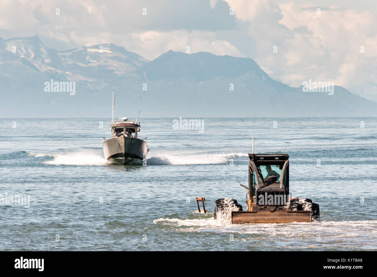 Fishing boats drive up to an awaiting tractor tug that will carry them ...